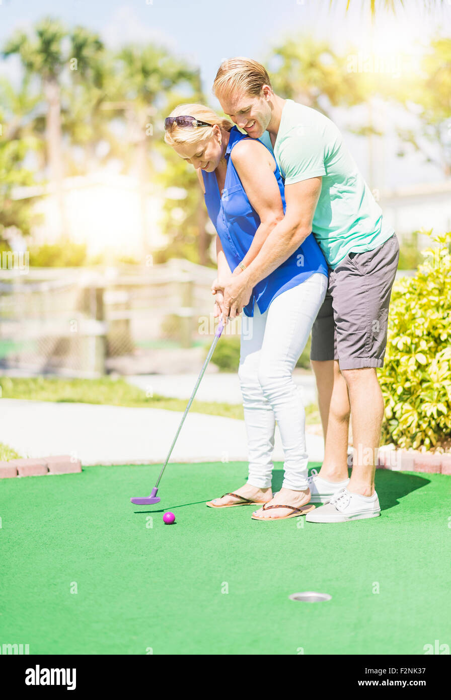 Caucasian couple playing miniature golf Stock Photo - Alamy