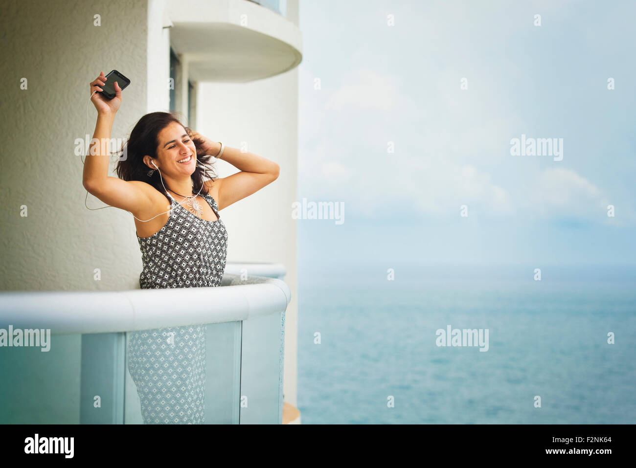 Hispanic woman dancing near ocean on hotel balcony Stock Photo - Alamy