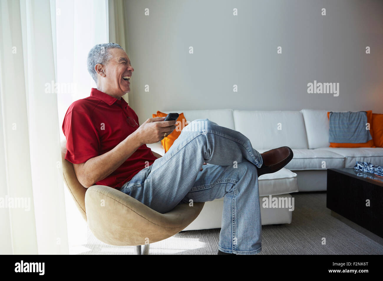 Older Black man using cell phone in living room Stock Photo - Alamy