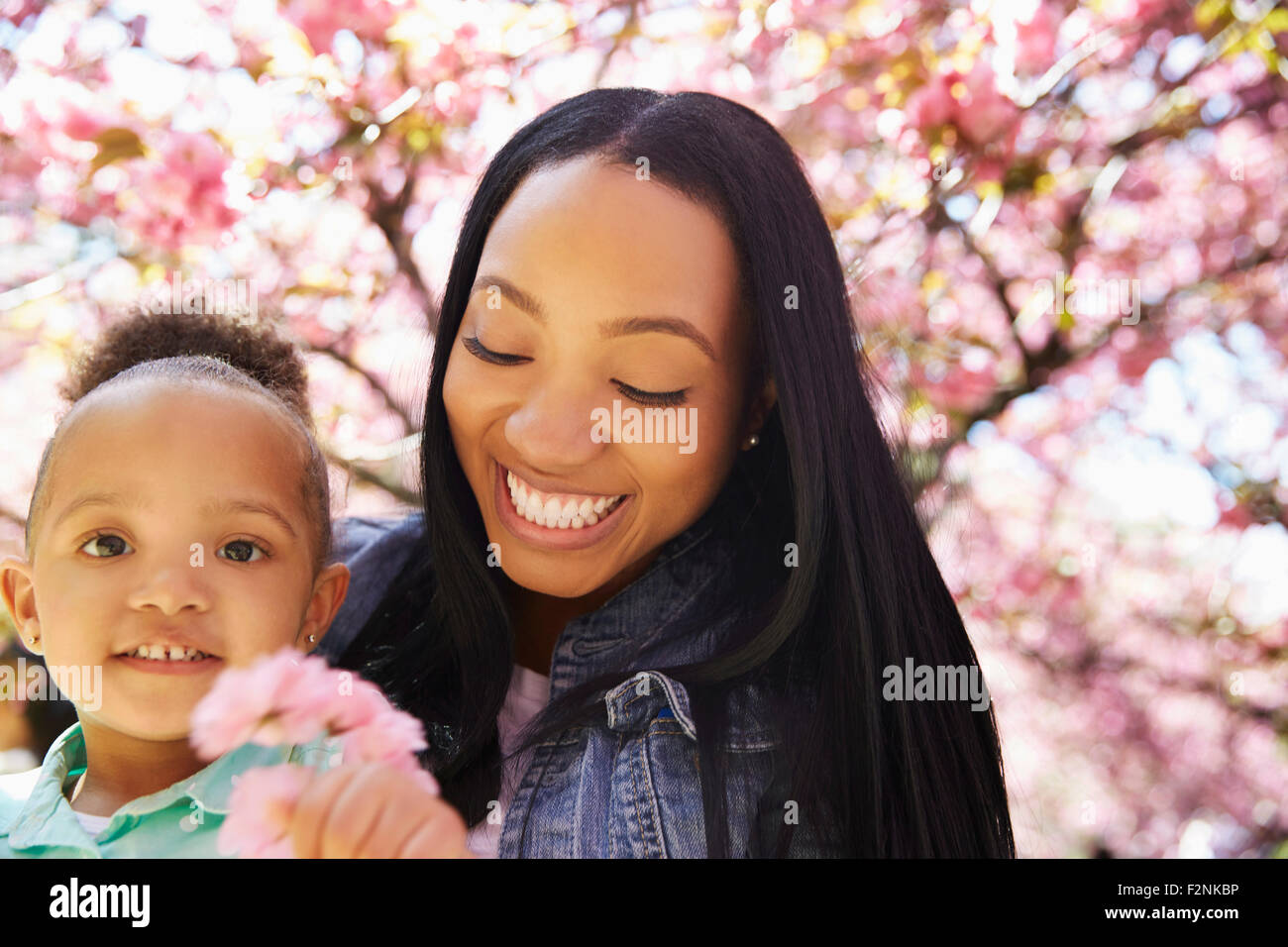 Mother and daughter under flowering tree in park Stock Photo - Alamy