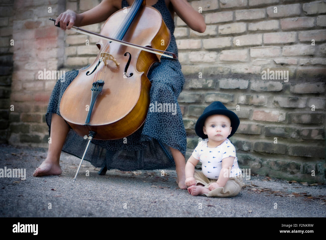 Mixed race musician playing cello with baby daughter Stock Photo - Alamy