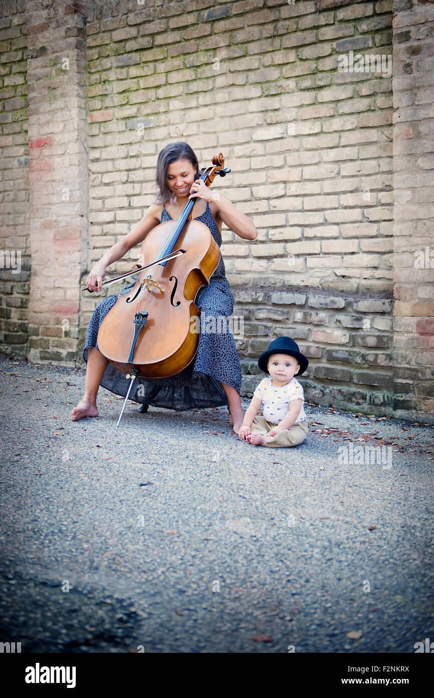 Mixed race musician playing cello with baby daughter Stock Photo - Alamy