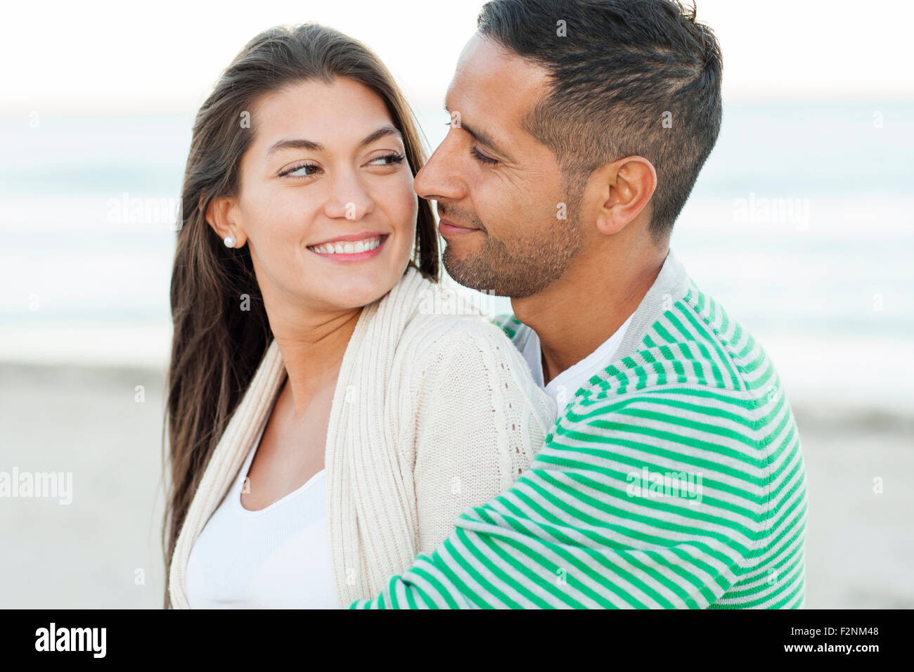 Hispanic couple hugging on beach Stock Photo - Alamy