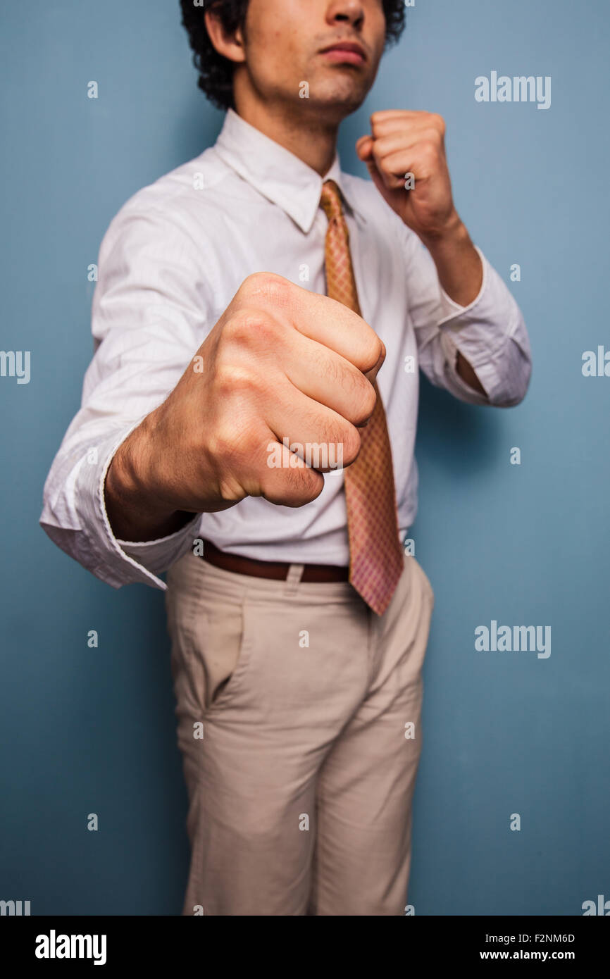 Young man standing by a blue wall throwing punches Stock Photo - Alamy