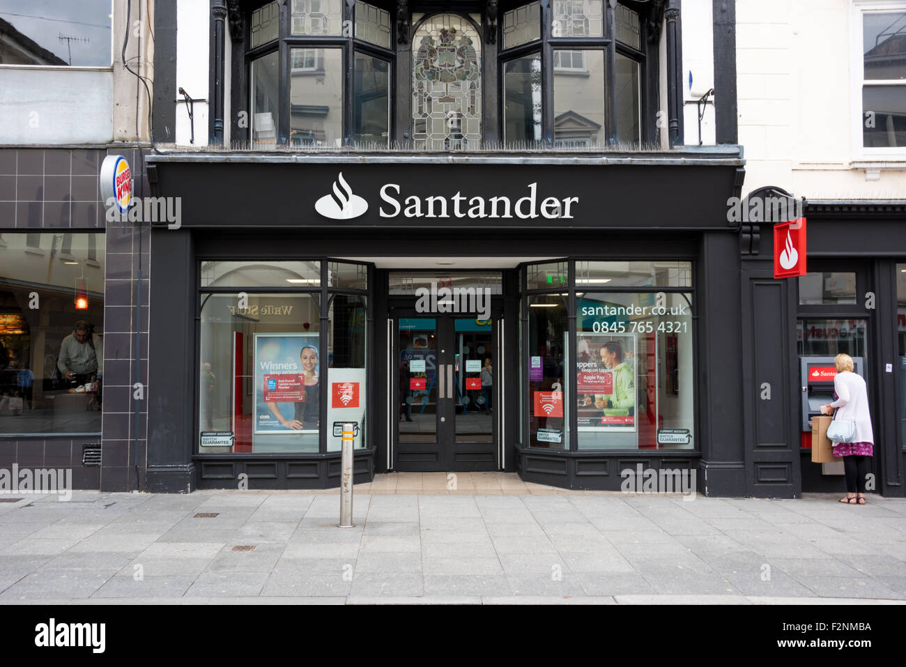 A Lady using the cash point at Santander Bank in Exeter City Centre UK ...