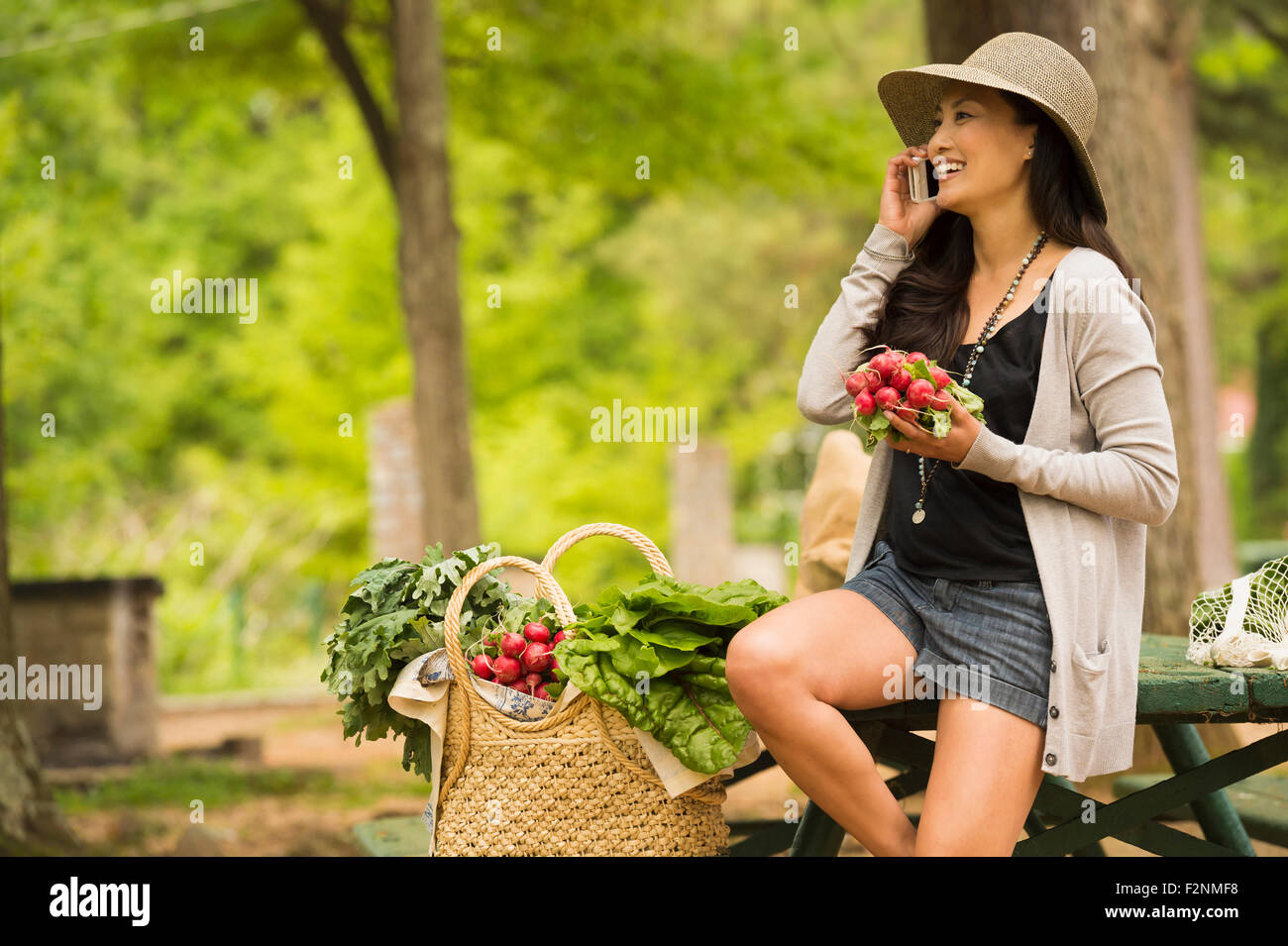 Asian woman talking on cell phone on picnic table Stock Photo - Alamy