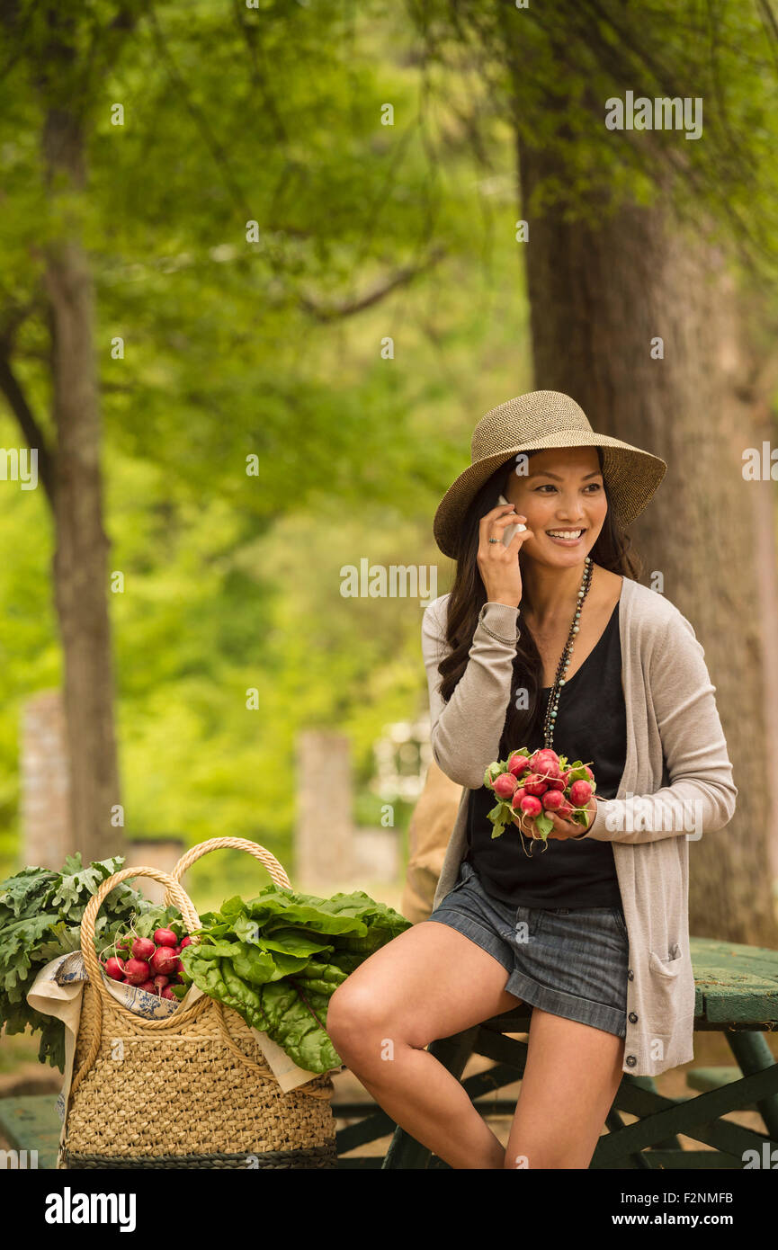 Asian woman talking on cell phone on picnic table Stock Photo - Alamy