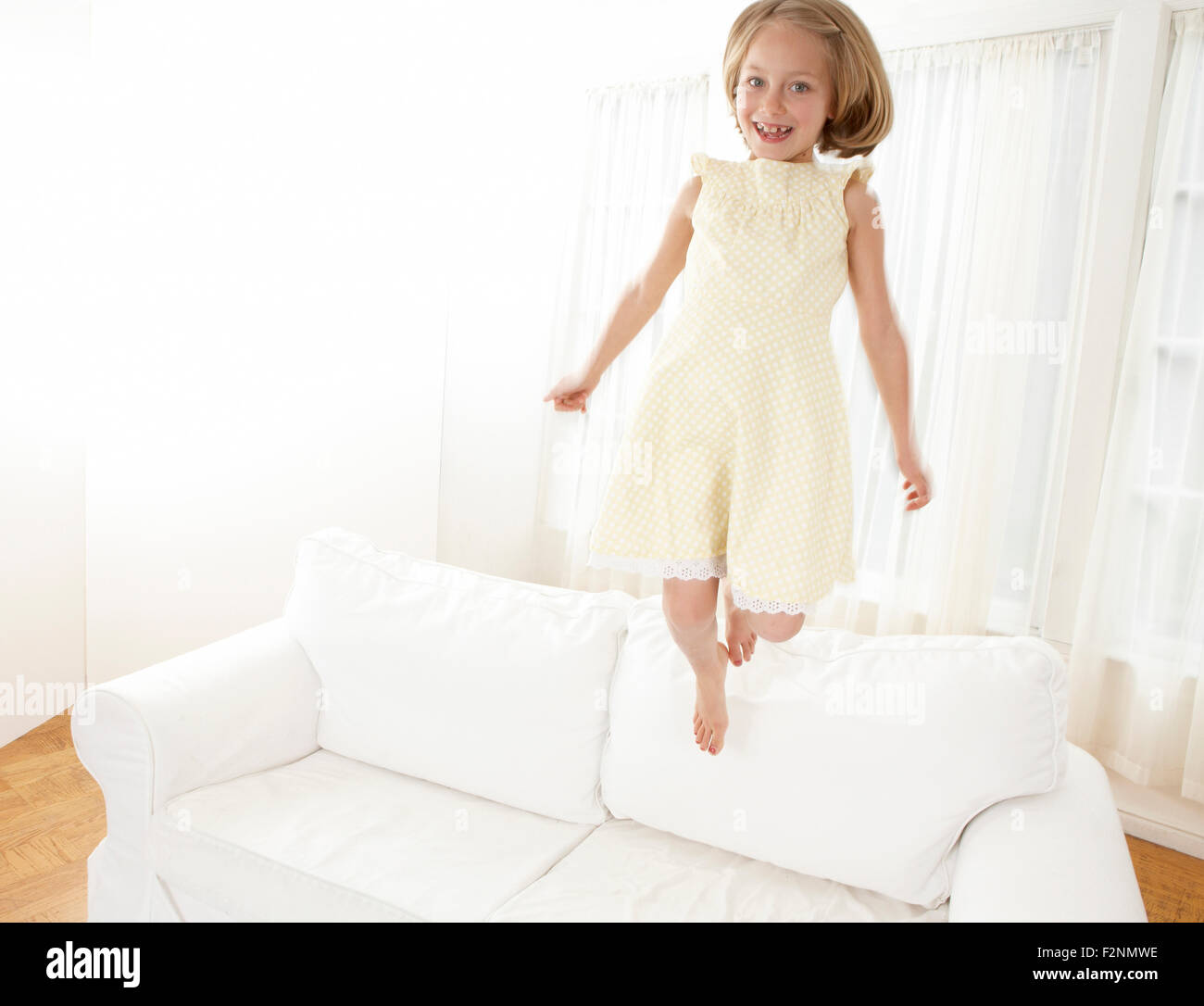 Caucasian girl jumping on sofa in living room Stock Photo - Alamy