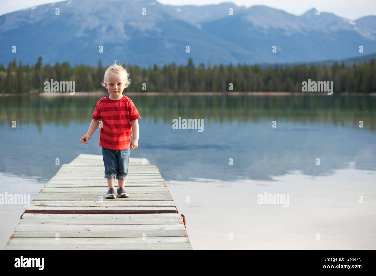 Caucasian boy walking on dock over remote lake Stock Photo - Alamy