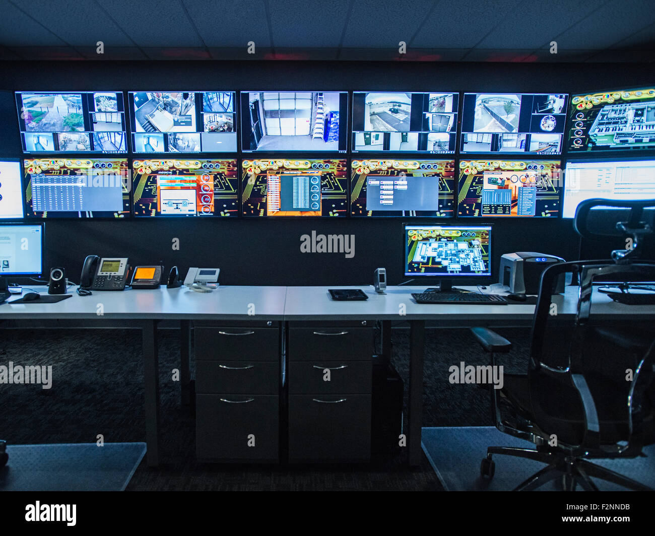 Monitors and empty desk in control room Stock Photo - Alamy