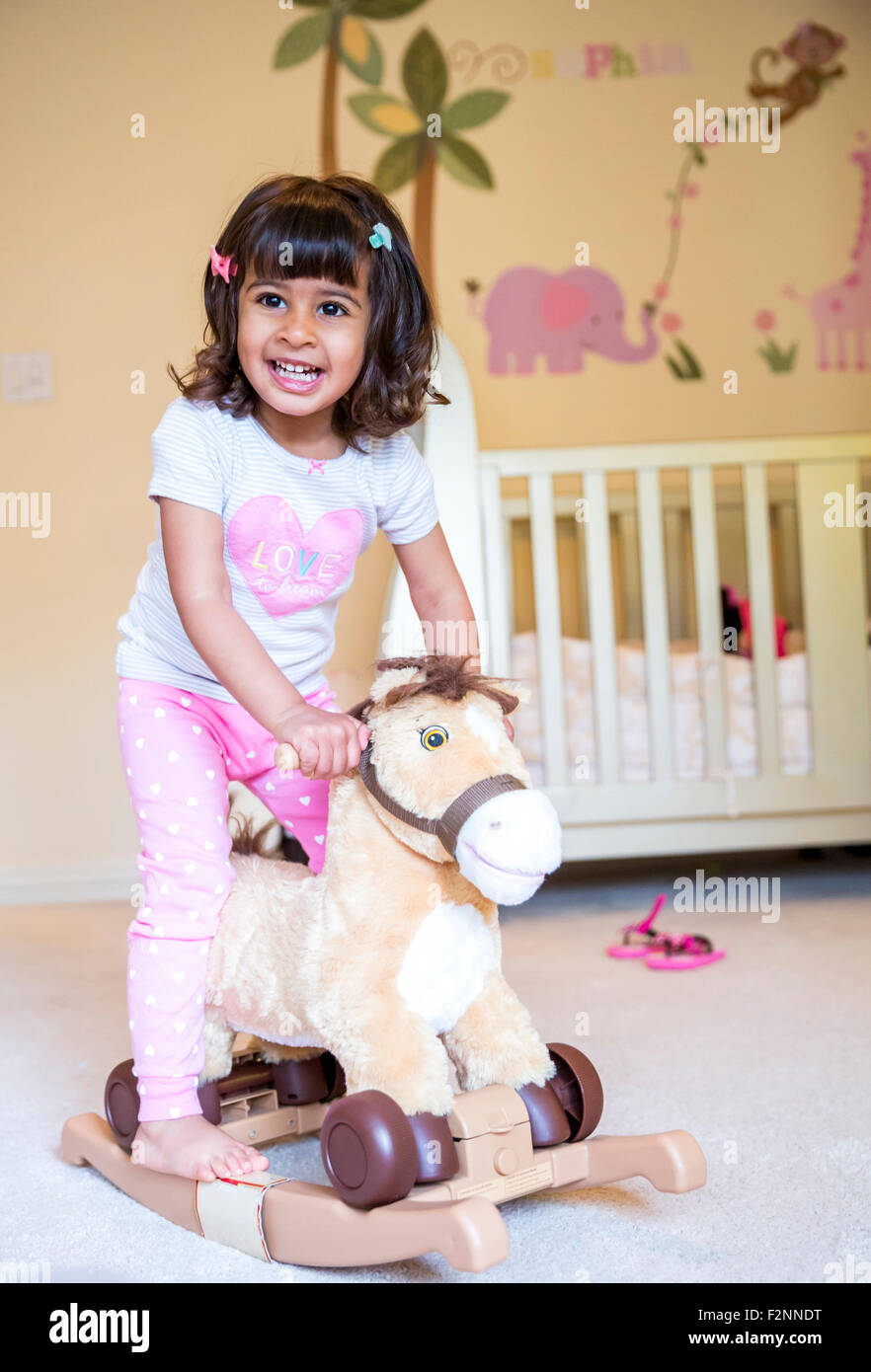 Girl riding rocking horse in nursery Stock Photo - Alamy