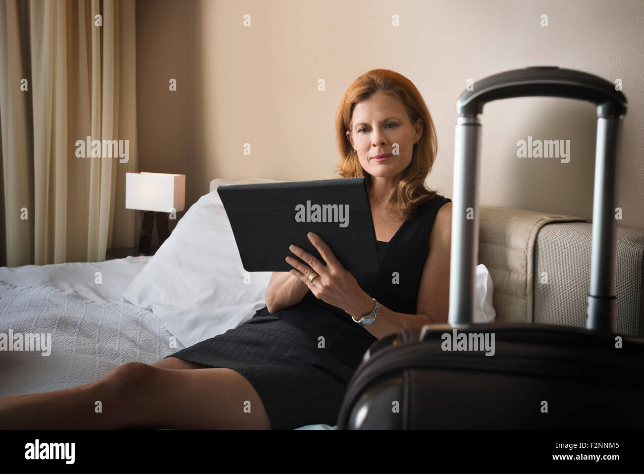 Businesswoman using digital tablet on hotel bed Stock Photo - Alamy