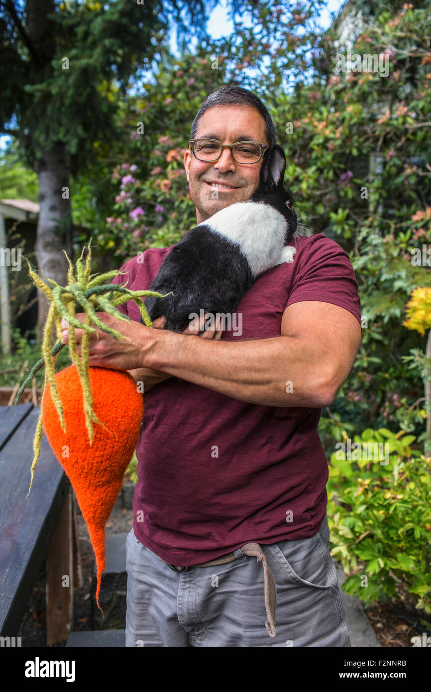 Mixed race man carrying rabbit and knitted carrot Stock Photo - Alamy