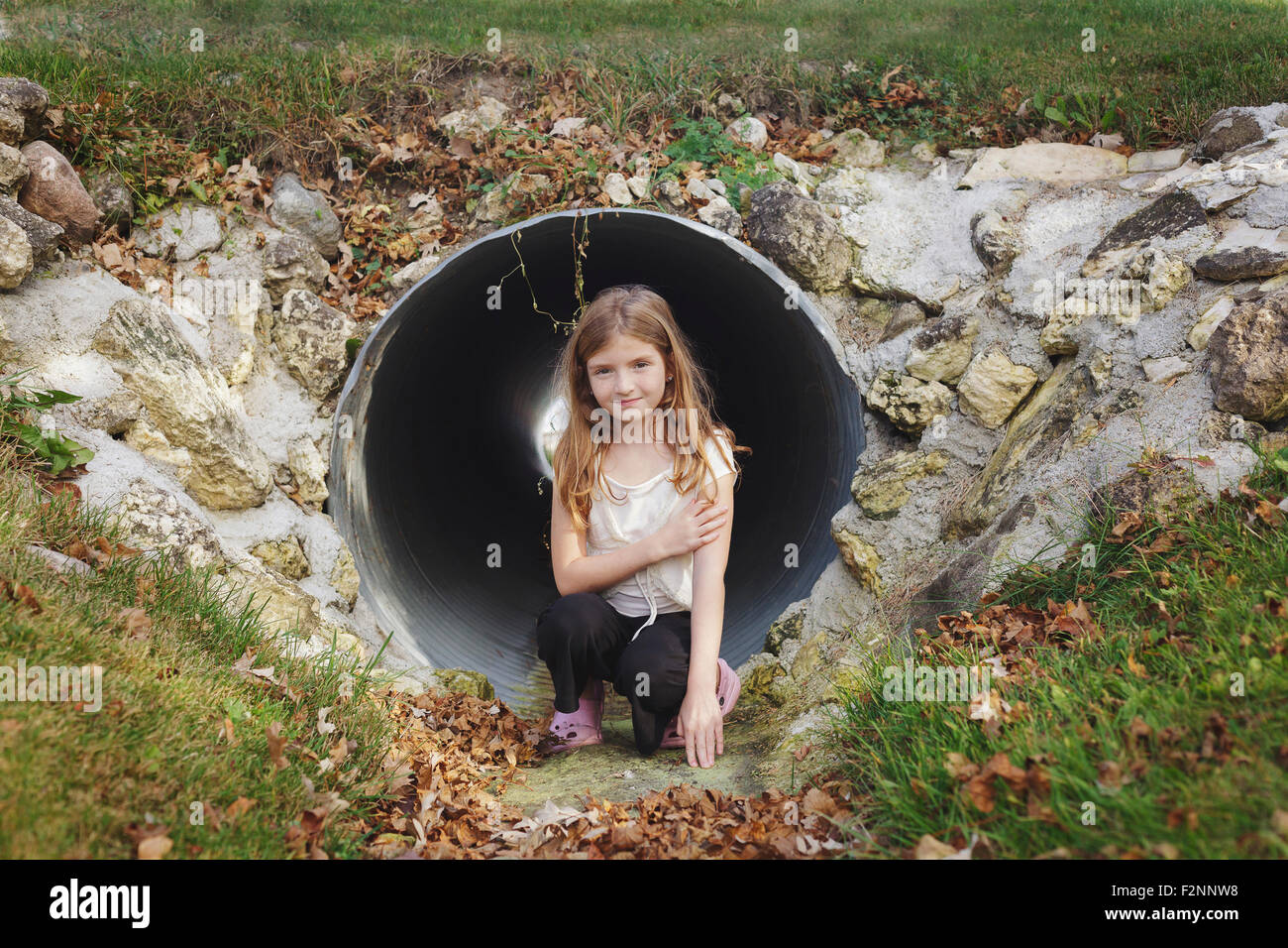 Caucasian girl climbing in storm drain tunnel Stock Photo - Alamy