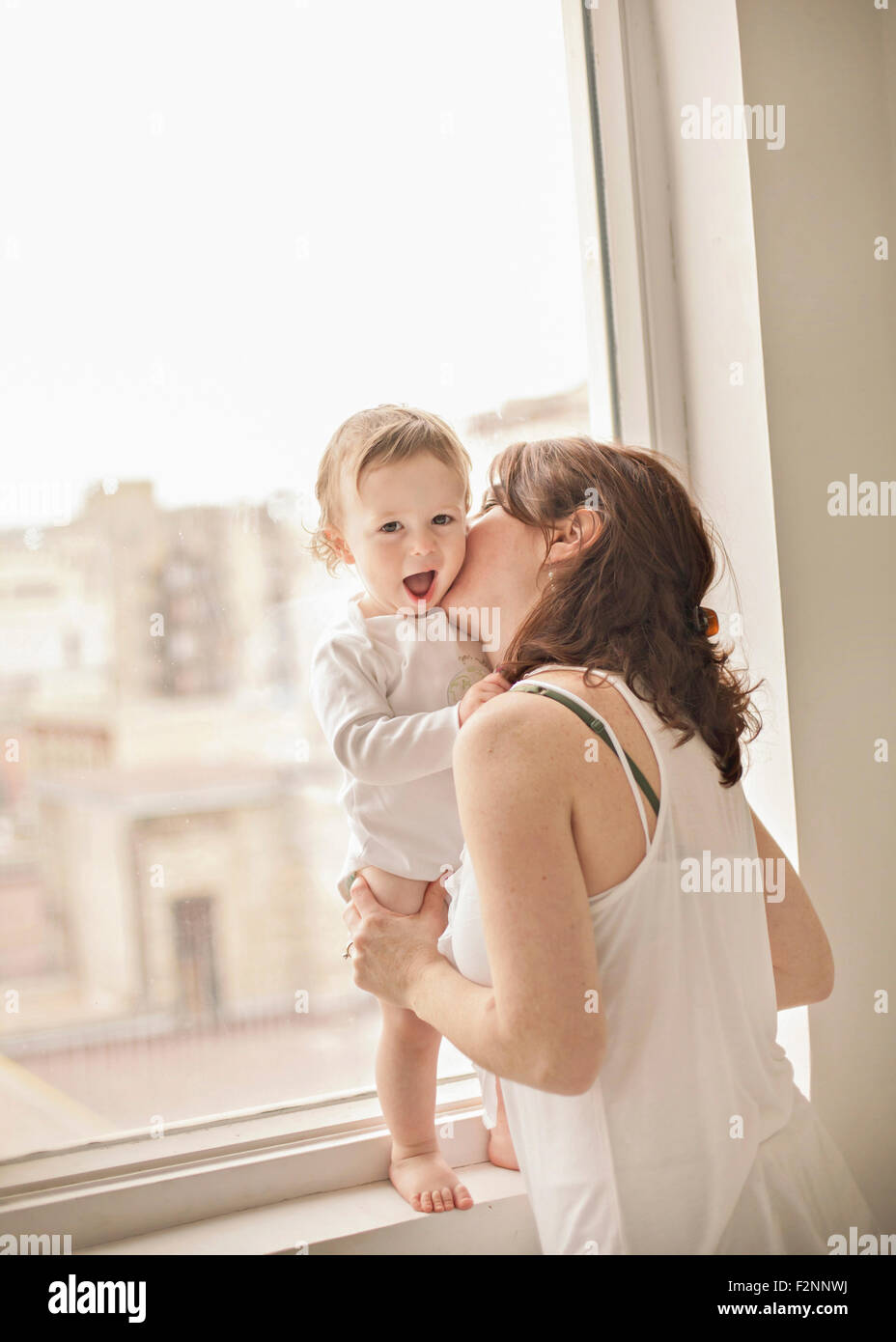 Caucasian mother kissing baby in window Stock Photo - Alamy