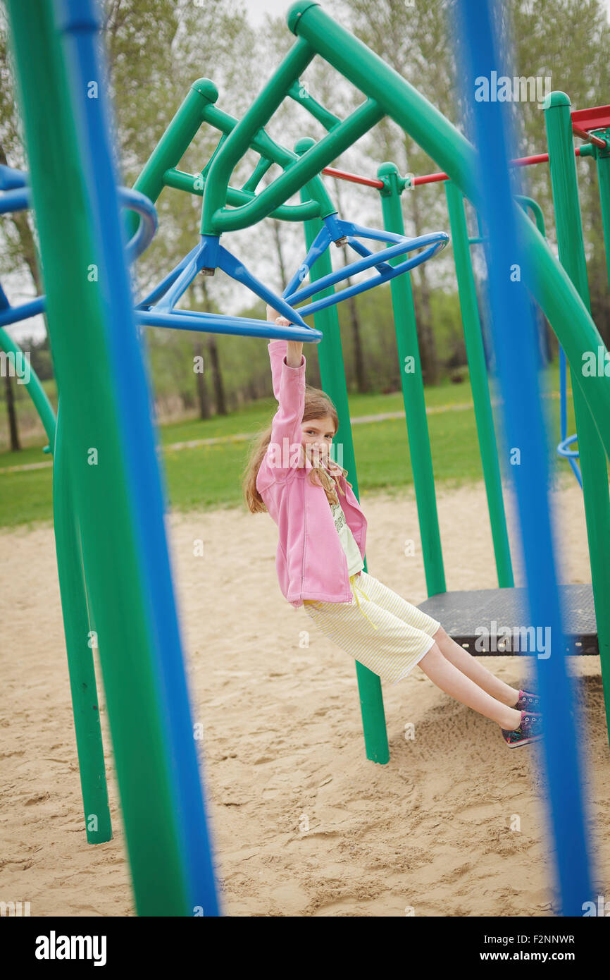 Caucasian girl hanging from structure in playground Stock Photo - Alamy