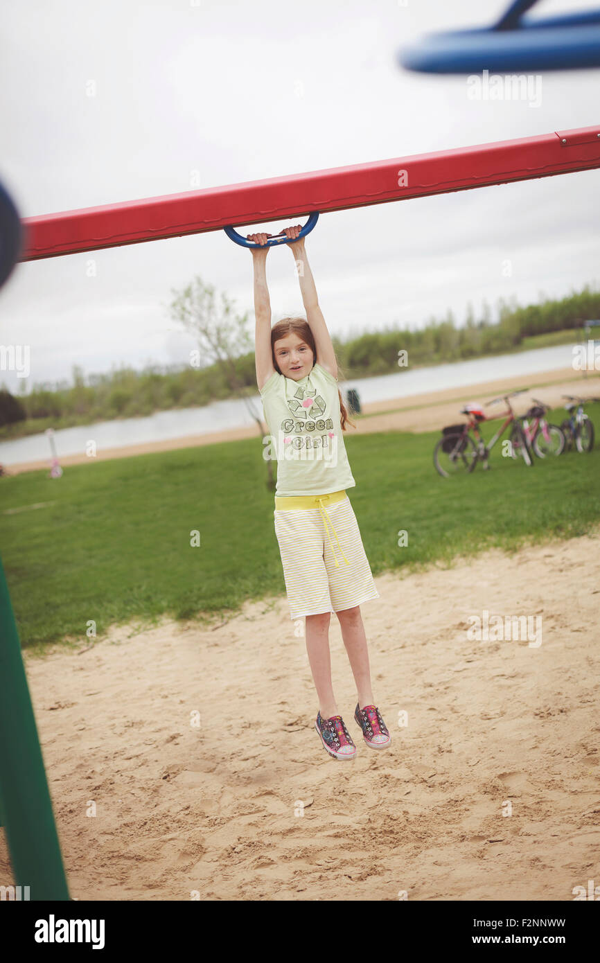 Caucasian girl hanging from structure in playground Stock Photo - Alamy