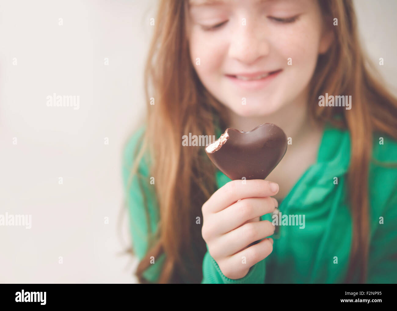 Caucasian girl eating heart-shaped chocolate Stock Photo - Alamy