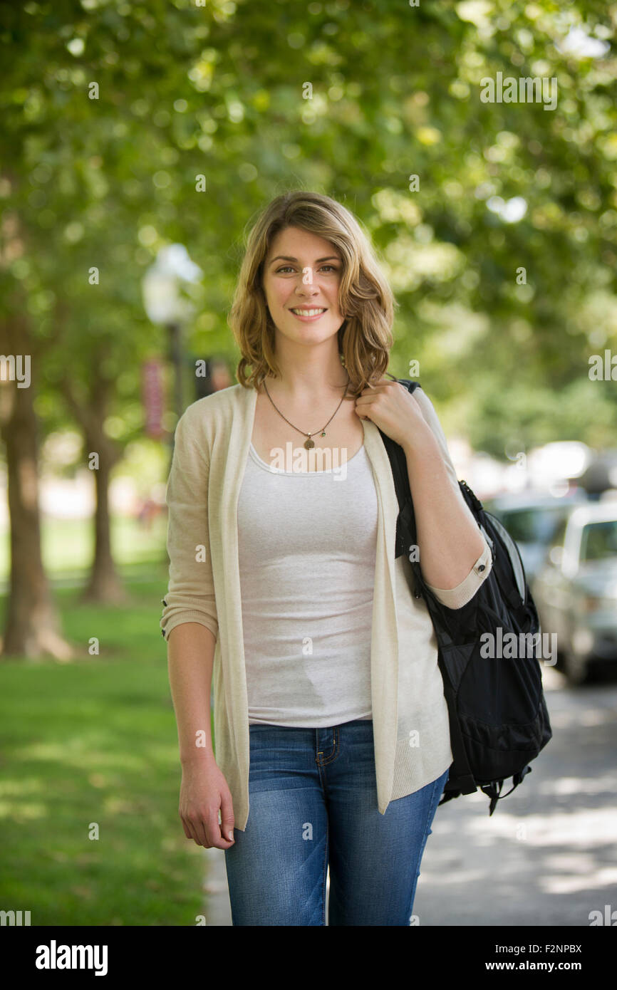 Caucasian student carrying backpack on sidewalk Stock Photo - Alamy