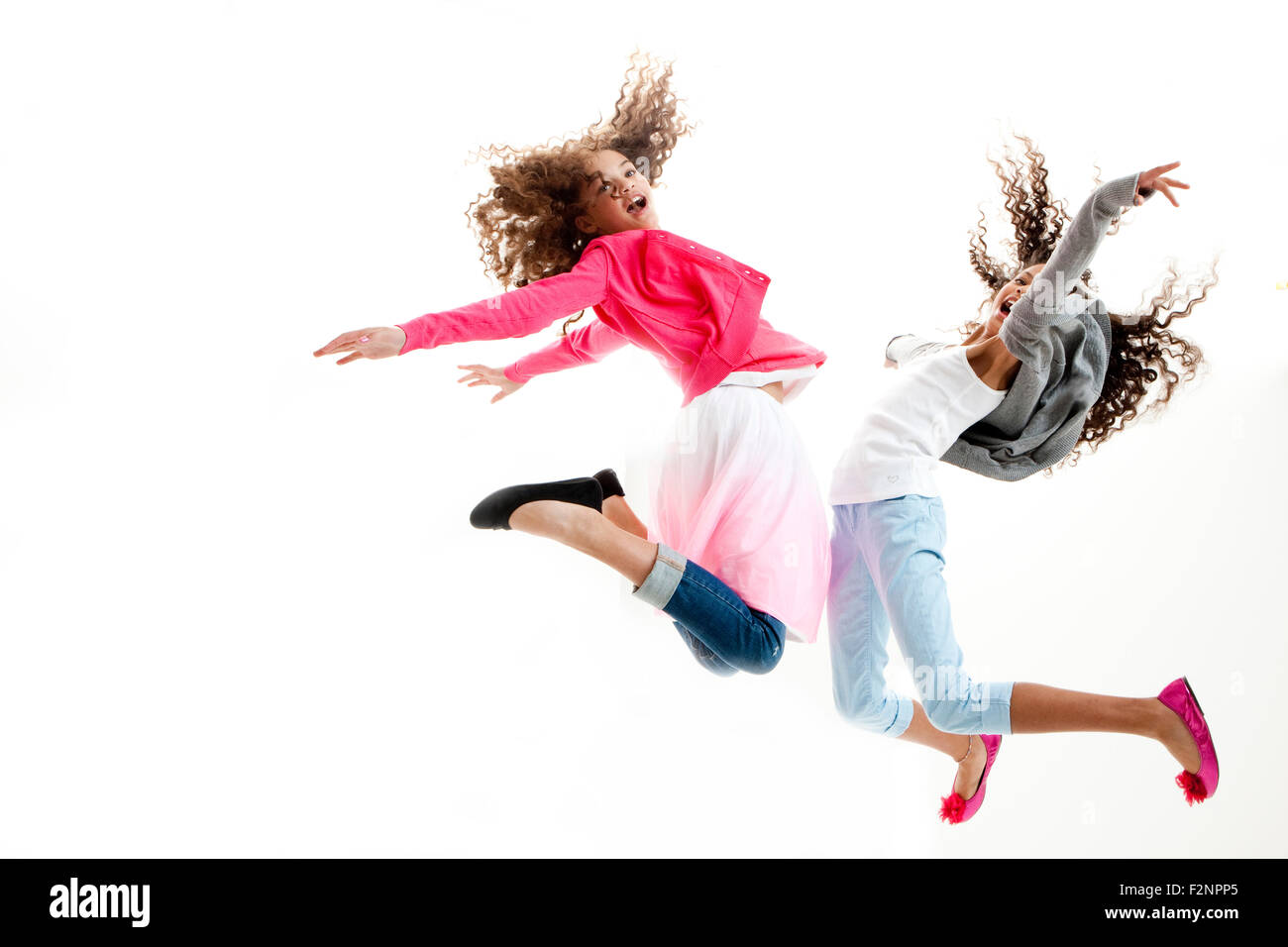Mixed race girls jumping for joy Stock Photo - Alamy