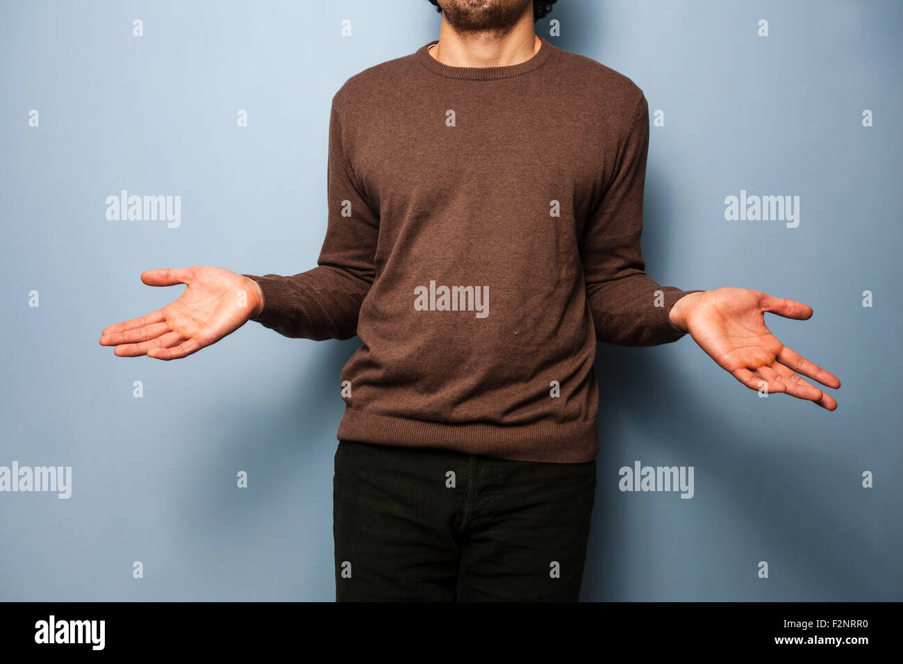 a young man shrugs, lifting his open hands toward the viewer Stock ...