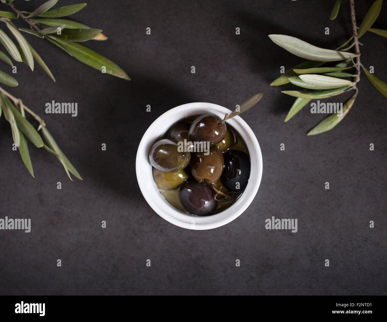 Black olives in dark background with olive tree leaves Stock Photo - Alamy
