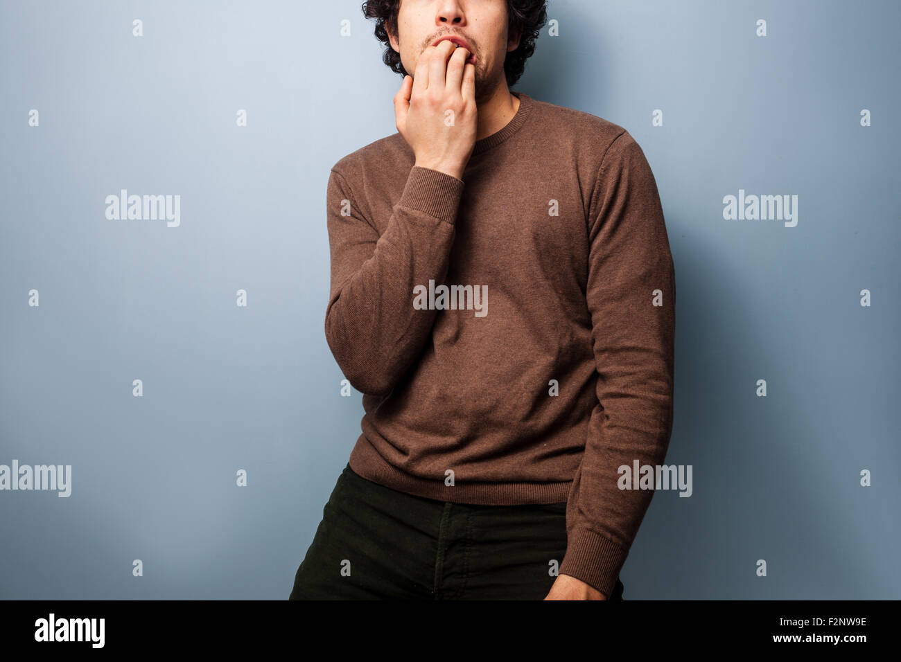 a scared and awkward young man stands hunched with his fingers to his ...