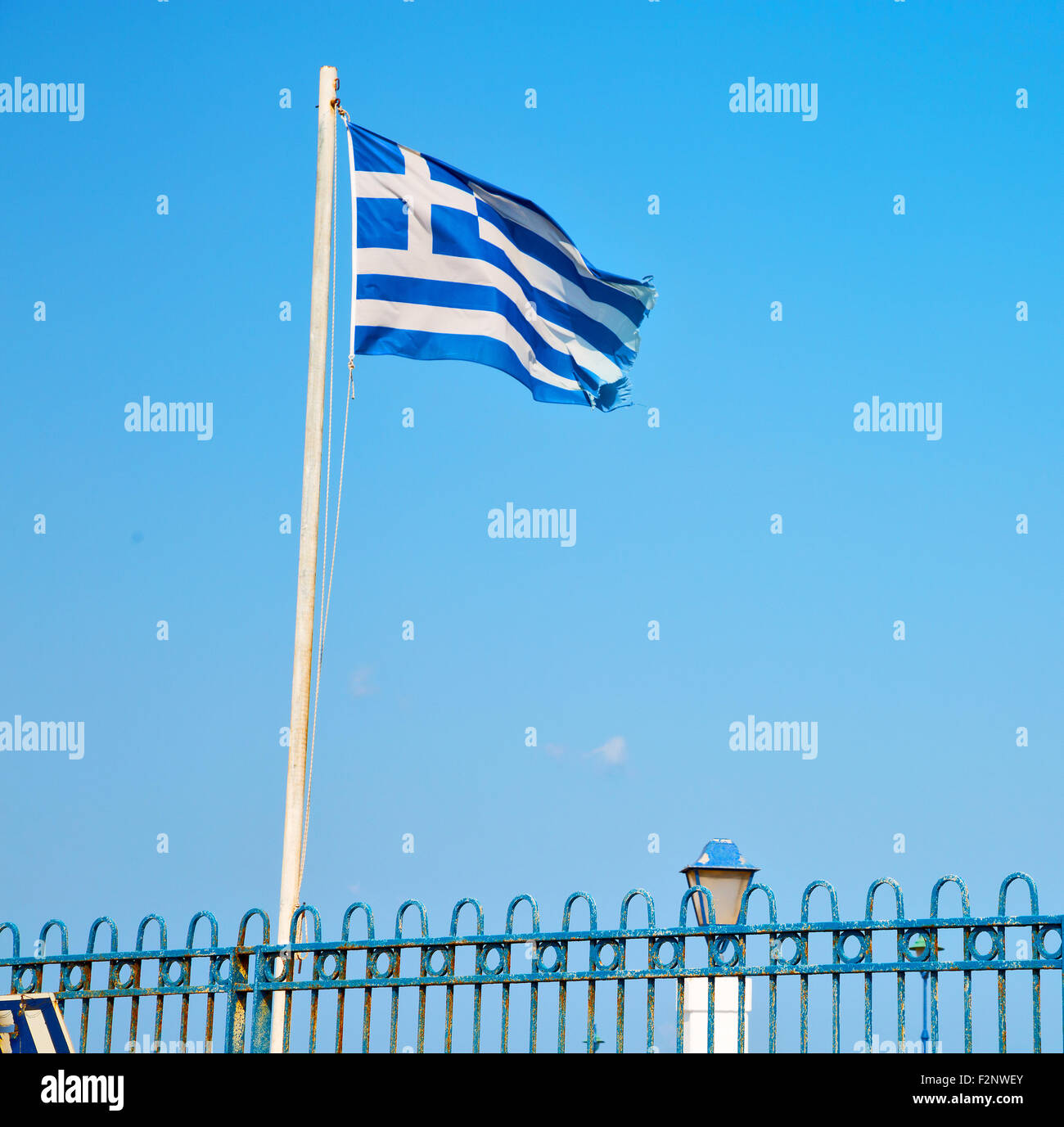 waving greece flag in the blue sky and flagpole Stock Photo - Alamy