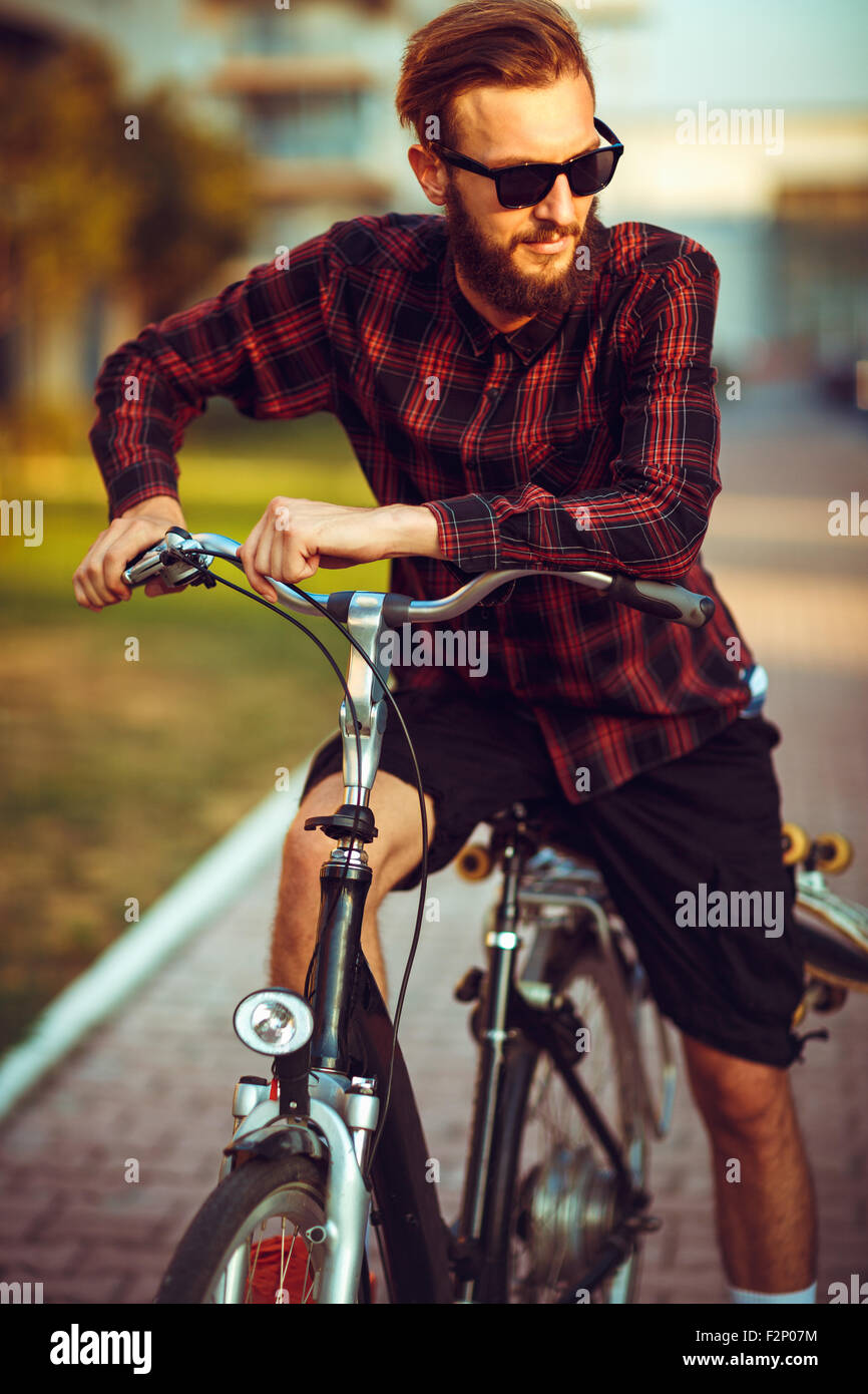 Young stylish man in sunglasses riding a bike on city street Stock ...