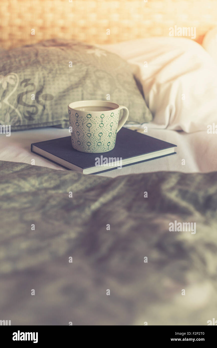 Book and cup of white coffee on a bed Stock Photo - Alamy