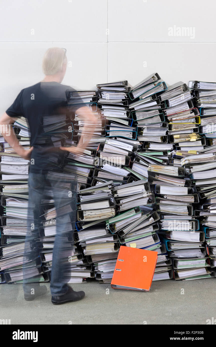 Man standing in front of pile of office files Stock Photo - Alamy