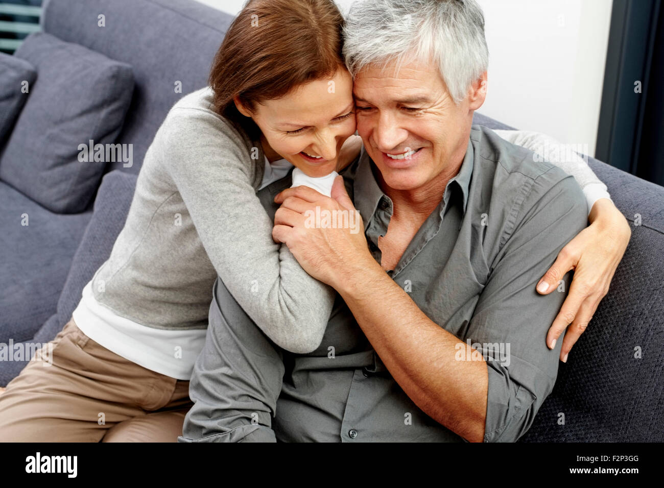 Happy couple sitting together on couch Stock Photo - Alamy