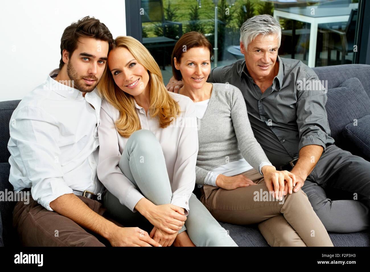Portrait of two couples sitting together on a couch Stock Photo - Alamy