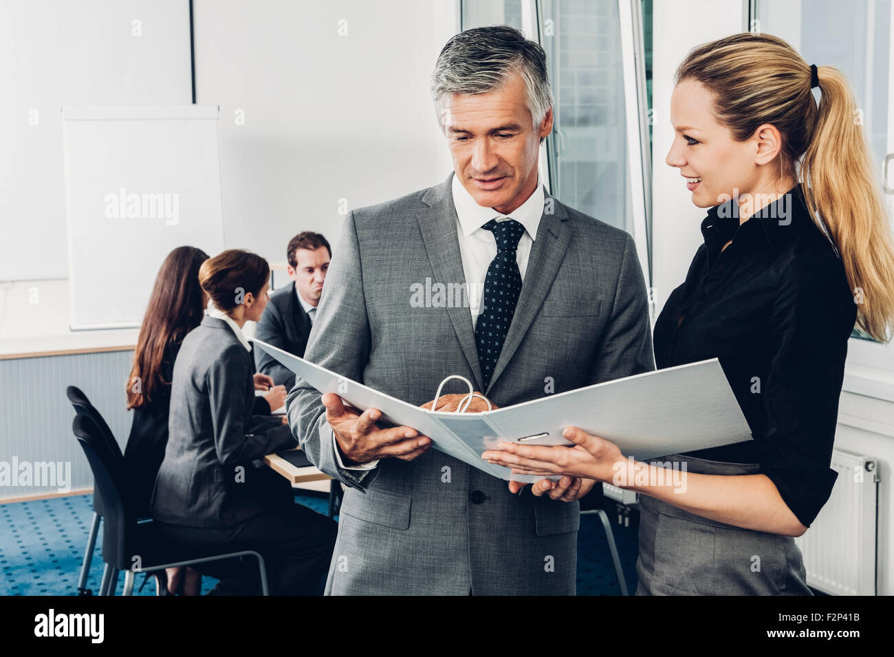 Business people reading report, standing in front of team Stock Photo ...