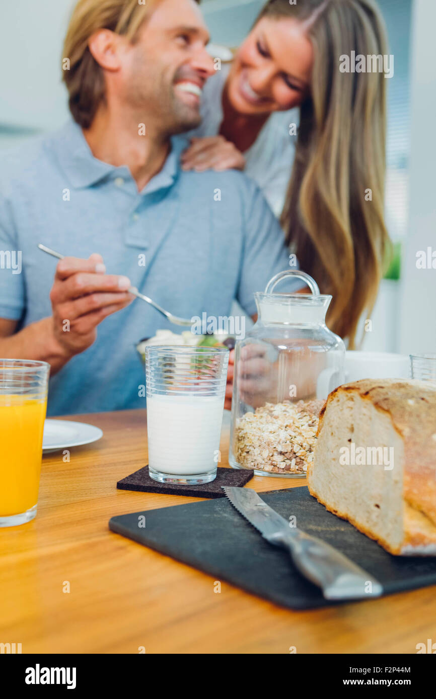 Happy couple eating at kitchen table Stock Photo - Alamy