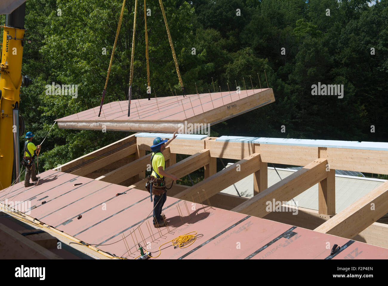 Construction workers install roof panels on Leed Platinum Common Ground ...