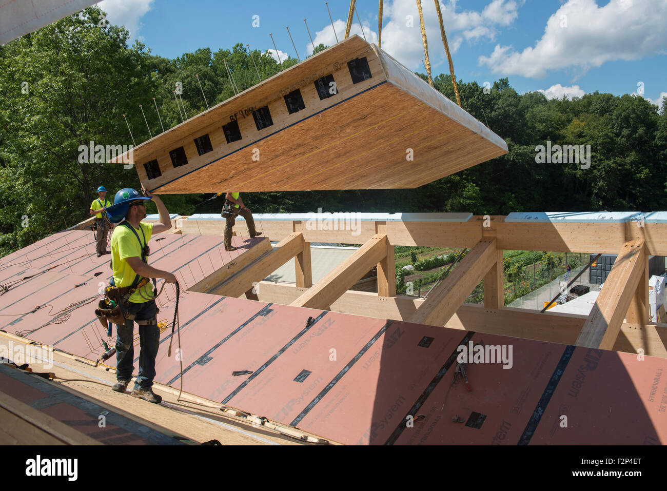 Construction workers install roof panels on Leed Platinum Common Ground ...