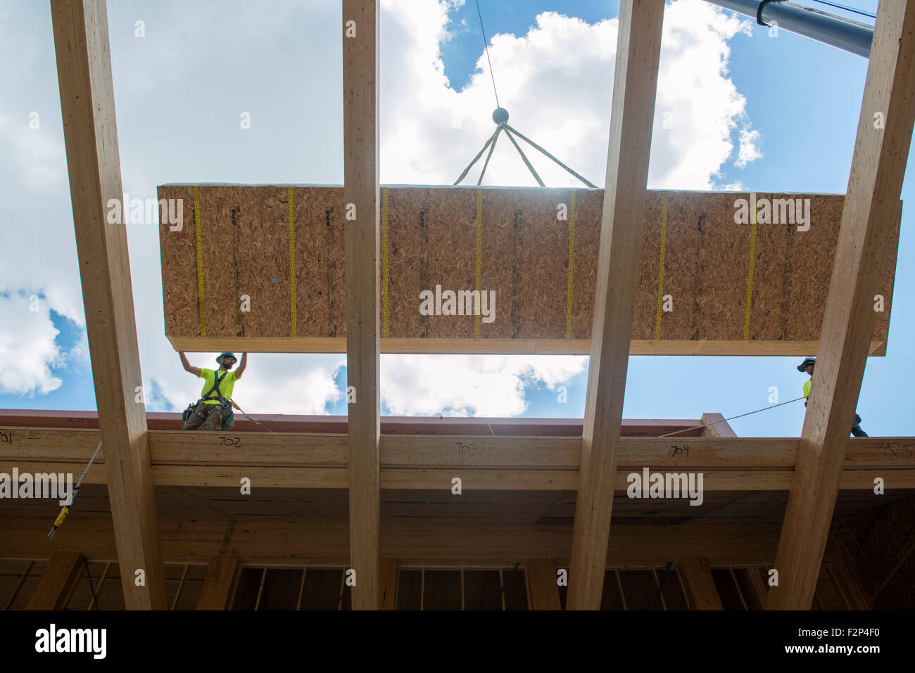 Construction workers install roof panels on Leed Platinum Common Ground ...