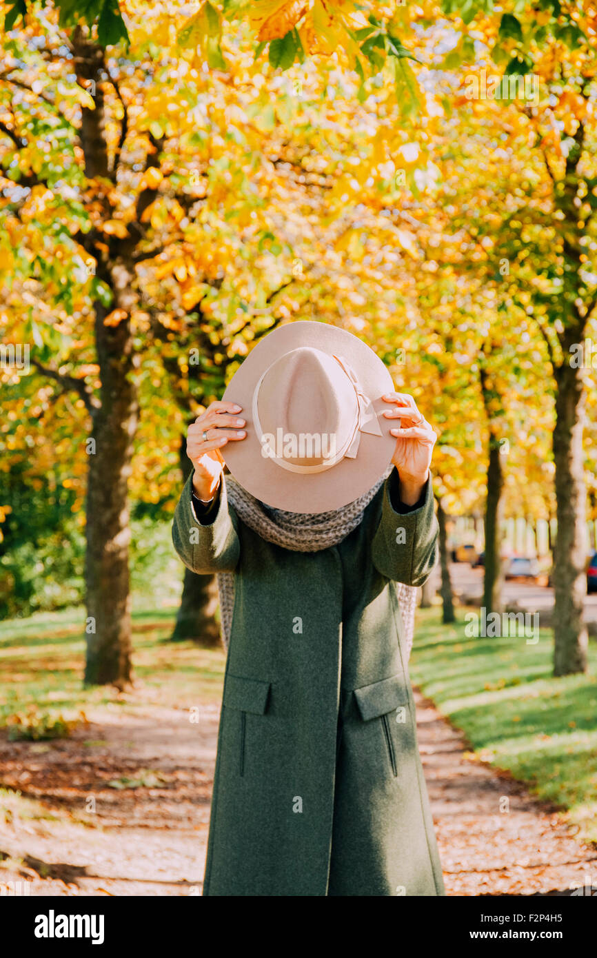 Woman hiding her face behind hat Stock Photo - Alamy