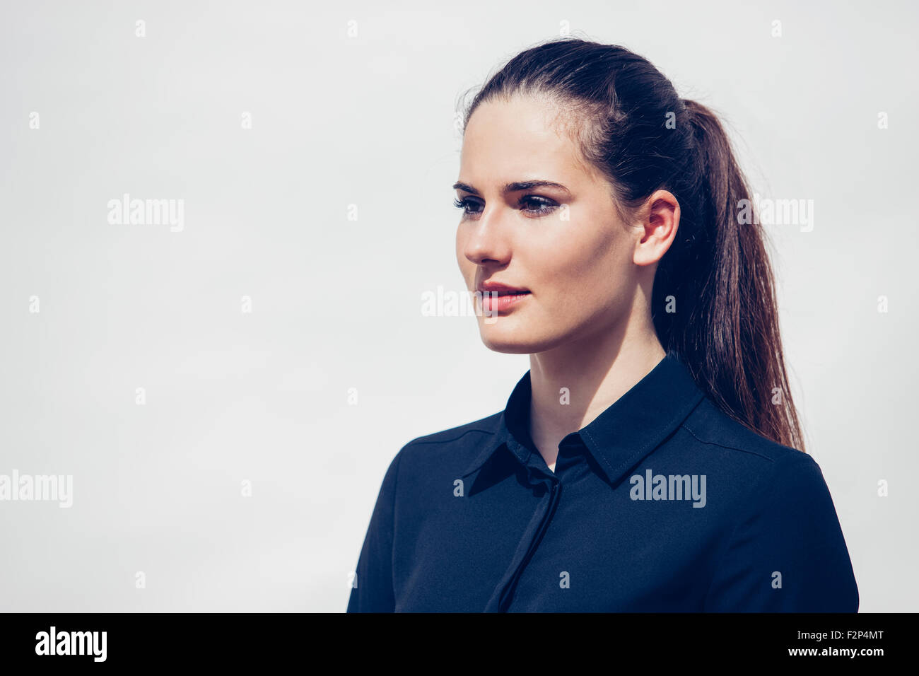 Portrait of young woman with ponytail in front of white background ...