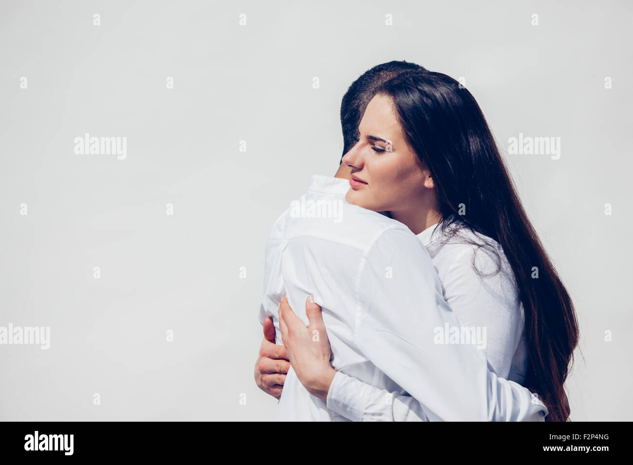 White dressed lovers with dark hair caressing each other in front of ...