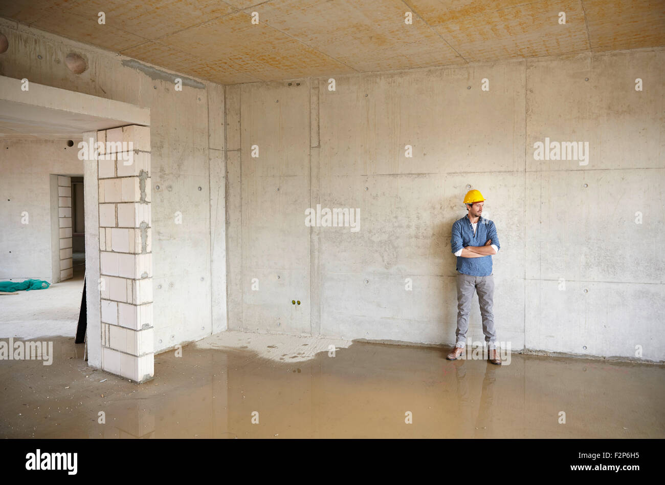 Man on construction site standing at large puddle Stock Photo - Alamy