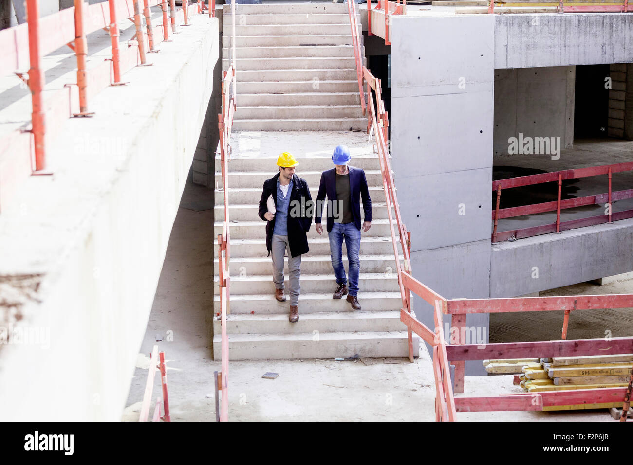 Two men on construction site walking down stairs Stock Photo - Alamy