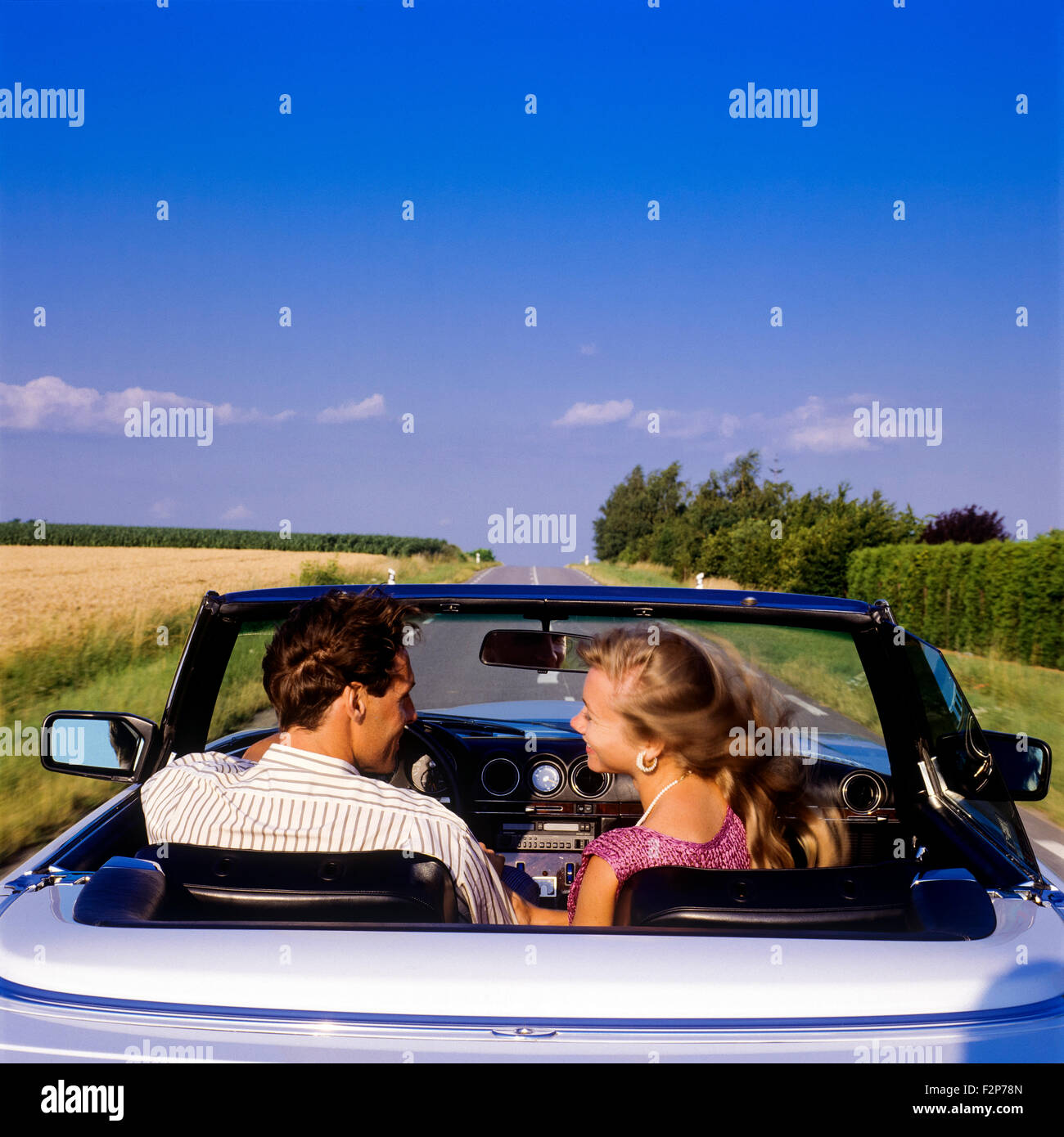 Rear view of a couple having fun while driving a Mercedes convertible ...