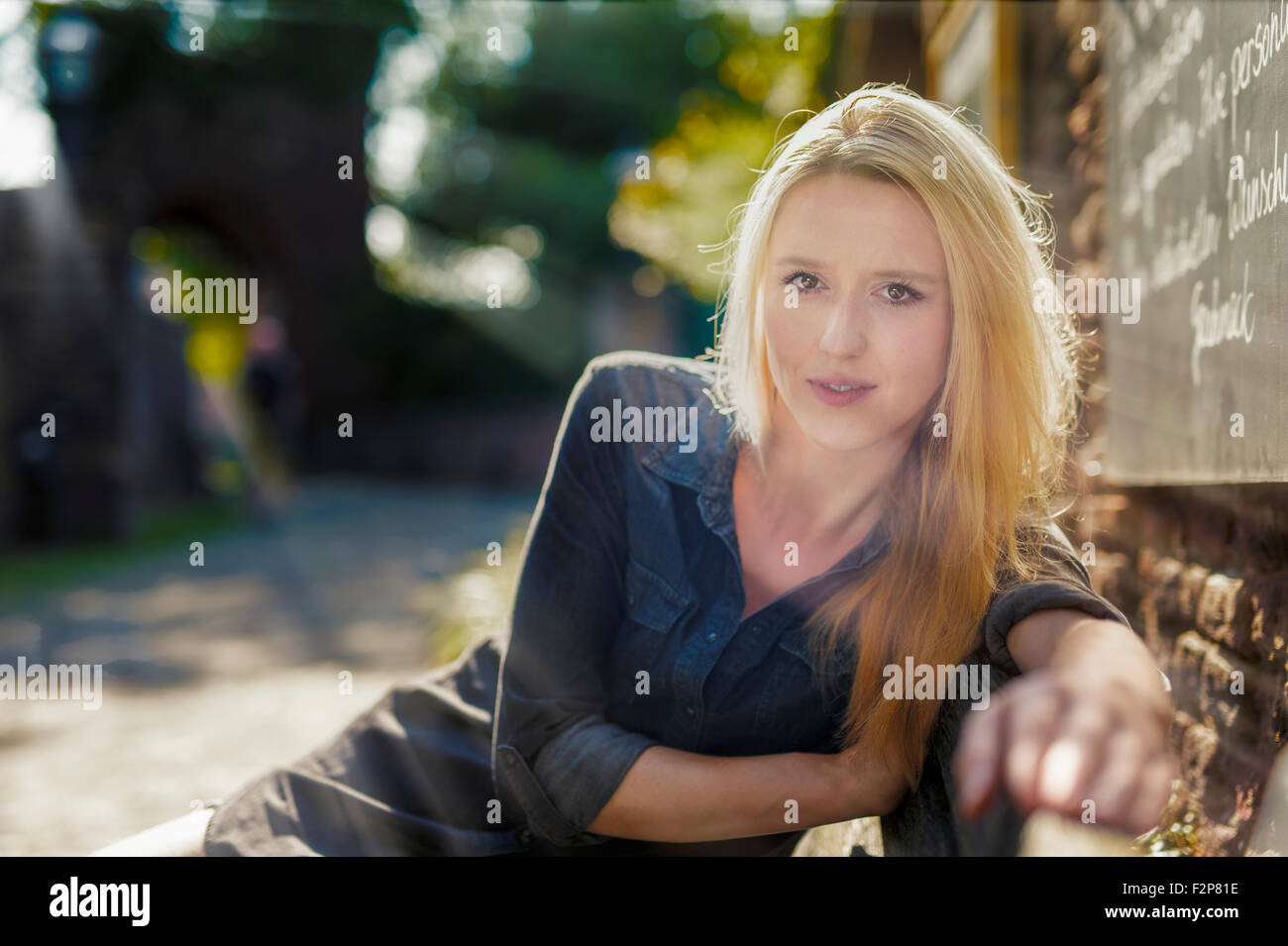 Portrait of blond woman sitting on a bench Stock Photo - Alamy