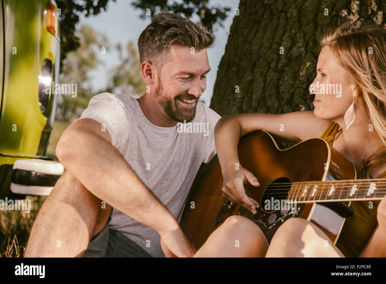 Couple making music at tree beside van Stock Photo - Alamy