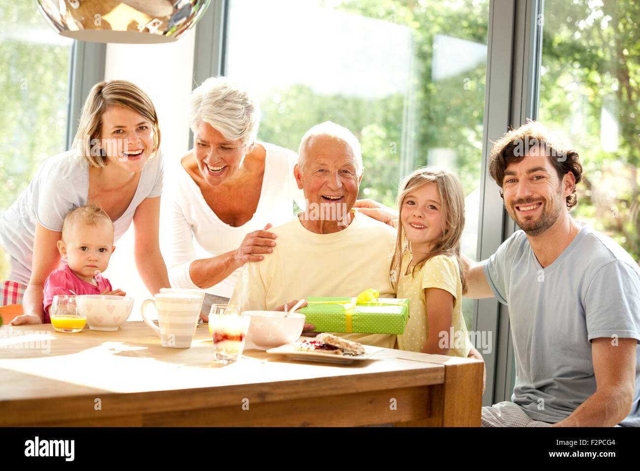 Portrait of happy extended family with present at breakfast table Stock ...