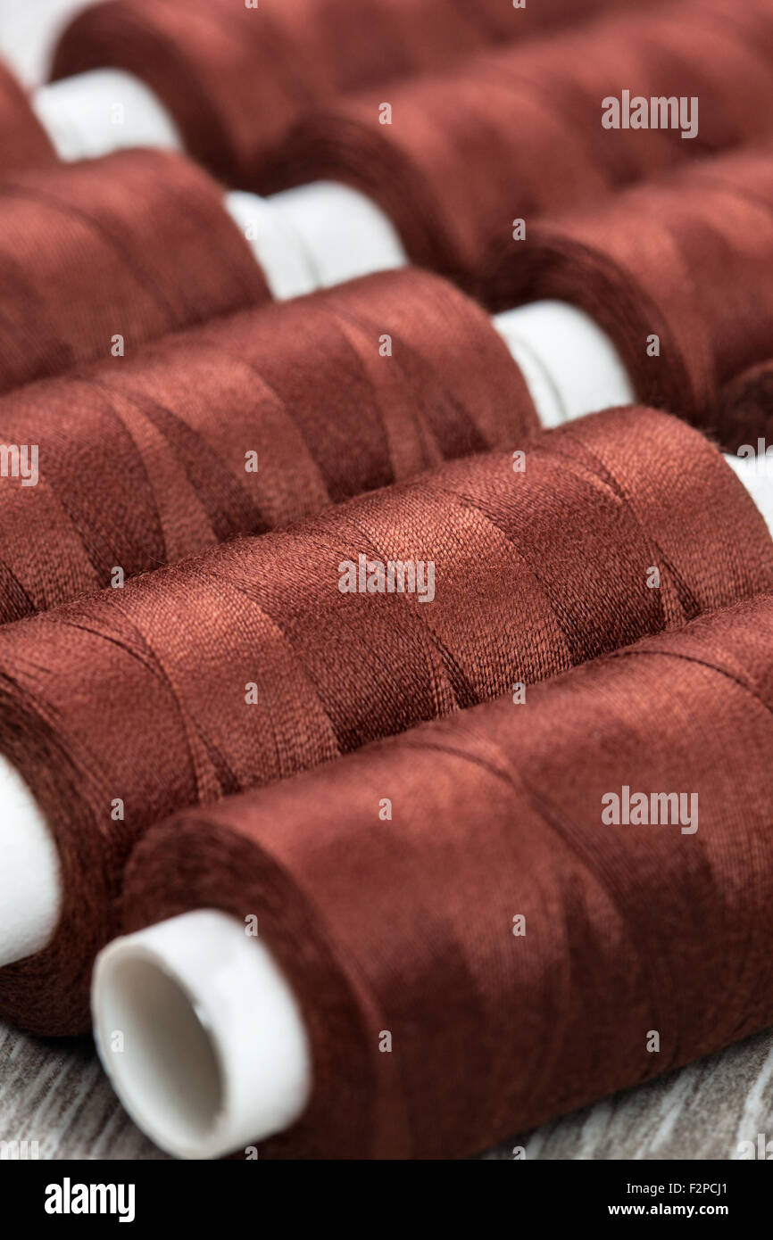background of the ranks of brown spools of thread close-up Stock Photo ...
