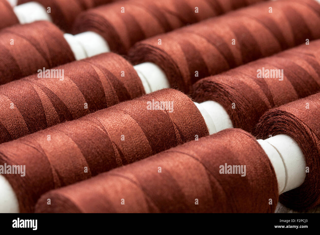 background of the ranks of brown spools of thread close-up Stock Photo ...