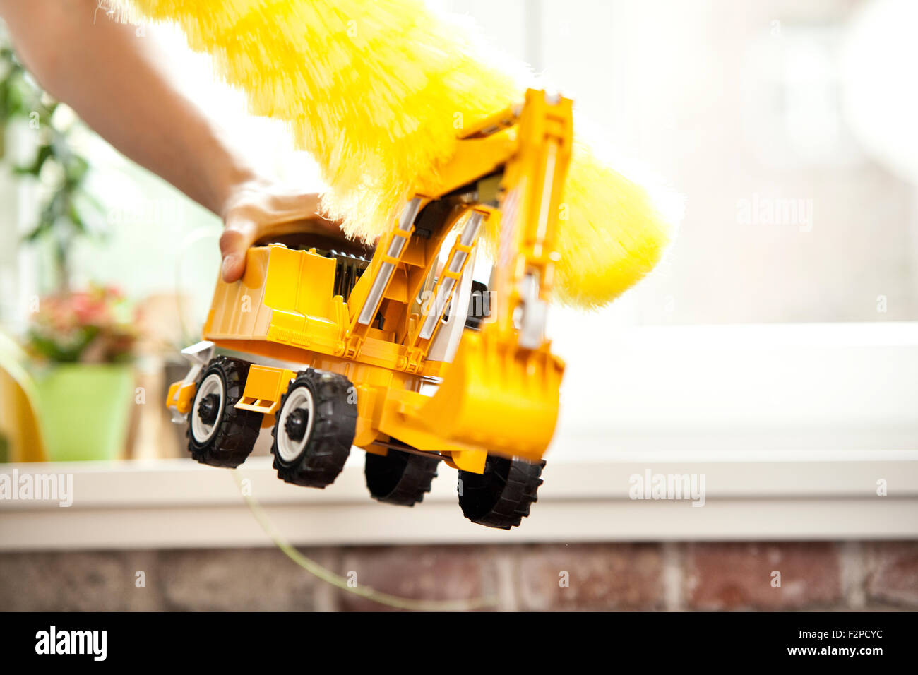 Woman dusting toy digger Stock Photo - Alamy